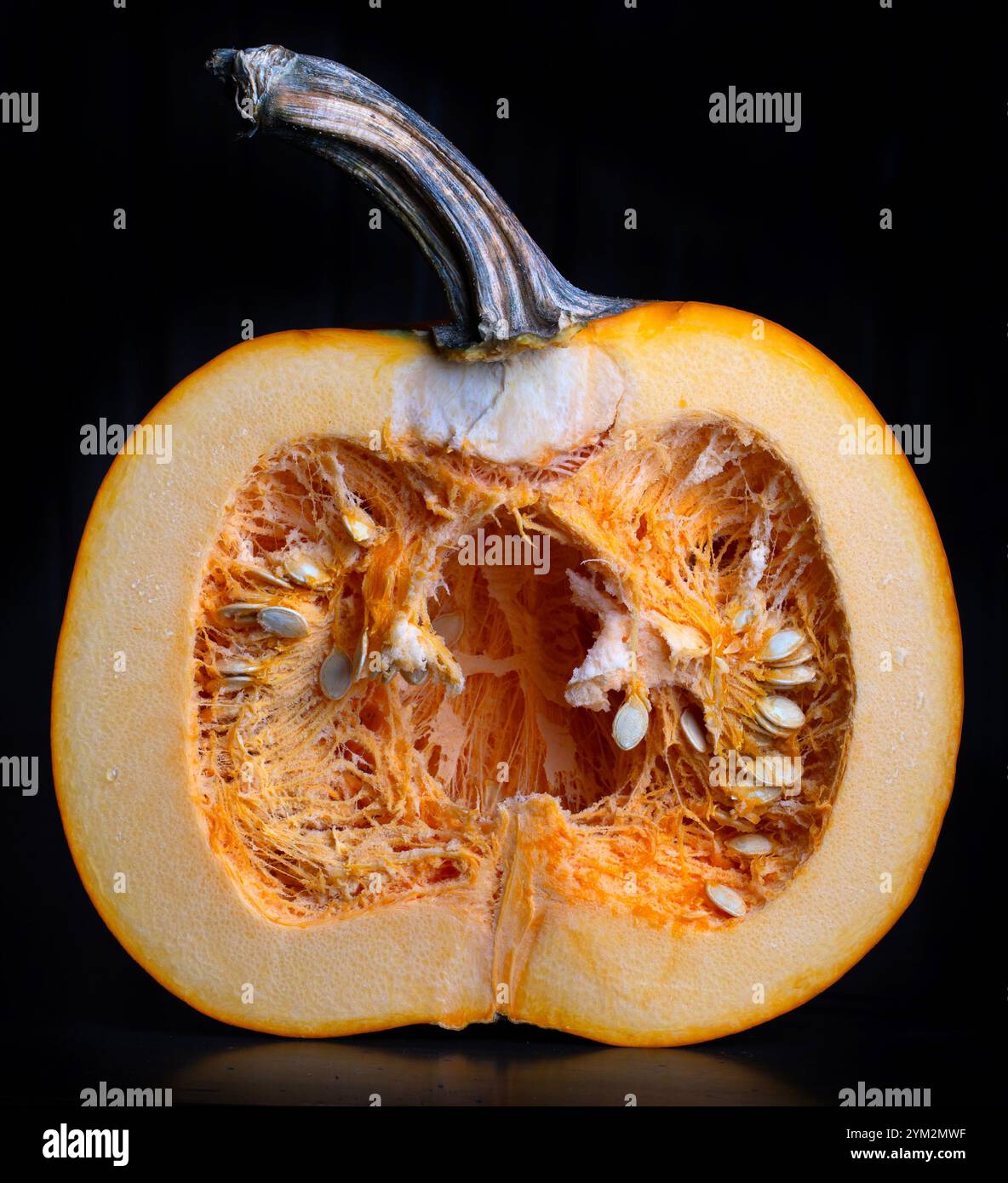 Pumpkin cut in half against black background Stock Photo - Alamy