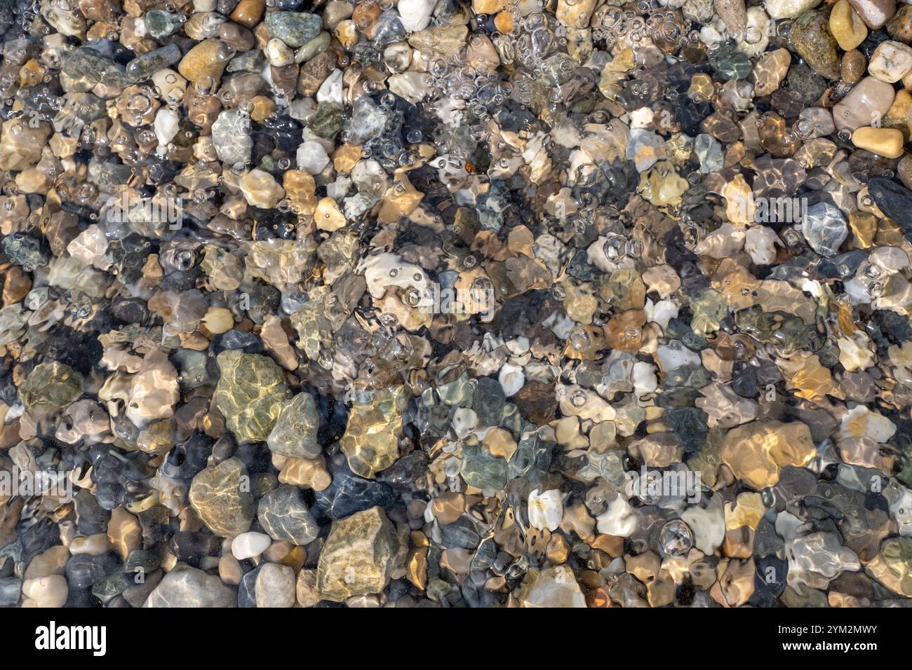 Pebbles underwater with ripples Stock Photo - Alamy