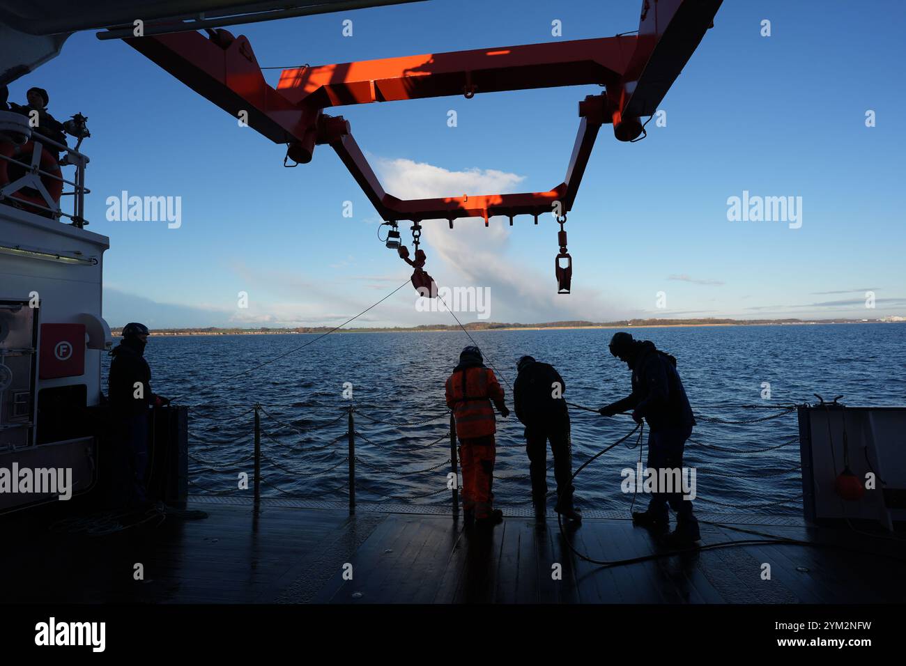 20 November 2024, Schleswig-Holstein, Kiel: Crew members pull a cable ...