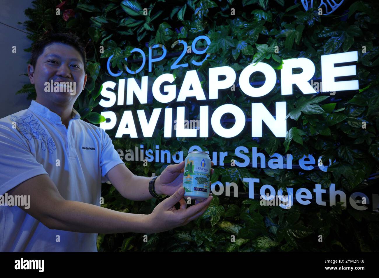 Nick Chow, part of the COP29 Singapore Pavilion team, poses for a photo with NEWBrew, beer made ...