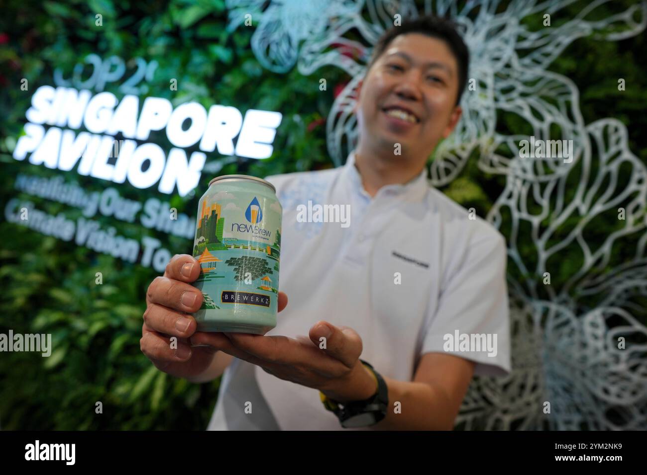 Nick Chow, part of the COP29 Singapore Pavilion team, poses for a photo with NEWBrew, beer made ...