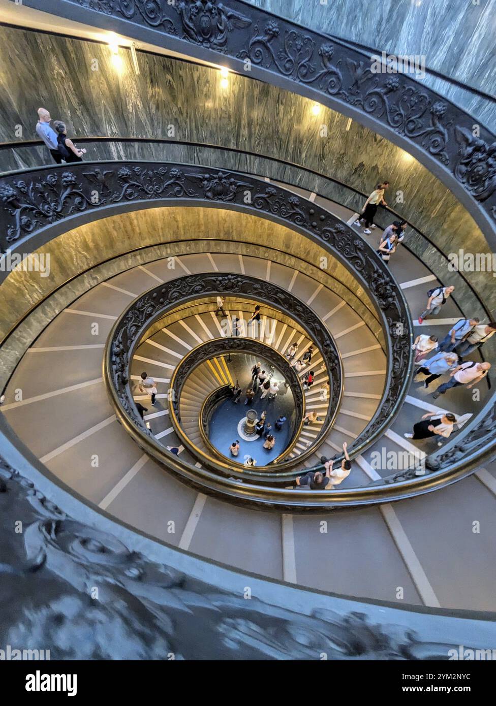 Aerial view of a busy spiral staircase with people ascending and ...