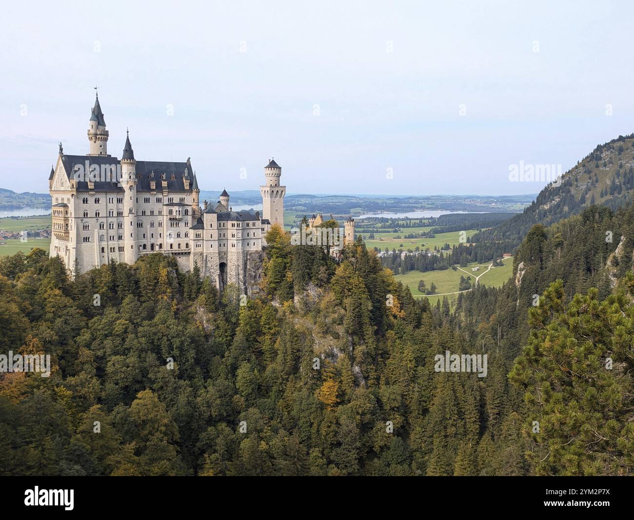 A castle above rolling hills and forest with a tranquil backdrop ...