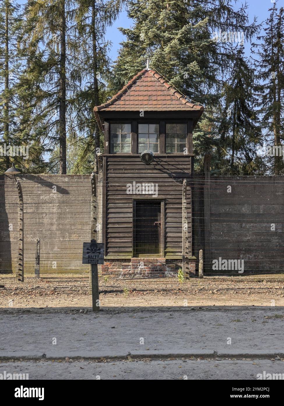 Wooden guard tower next to concrete walls with forest backdrop ...