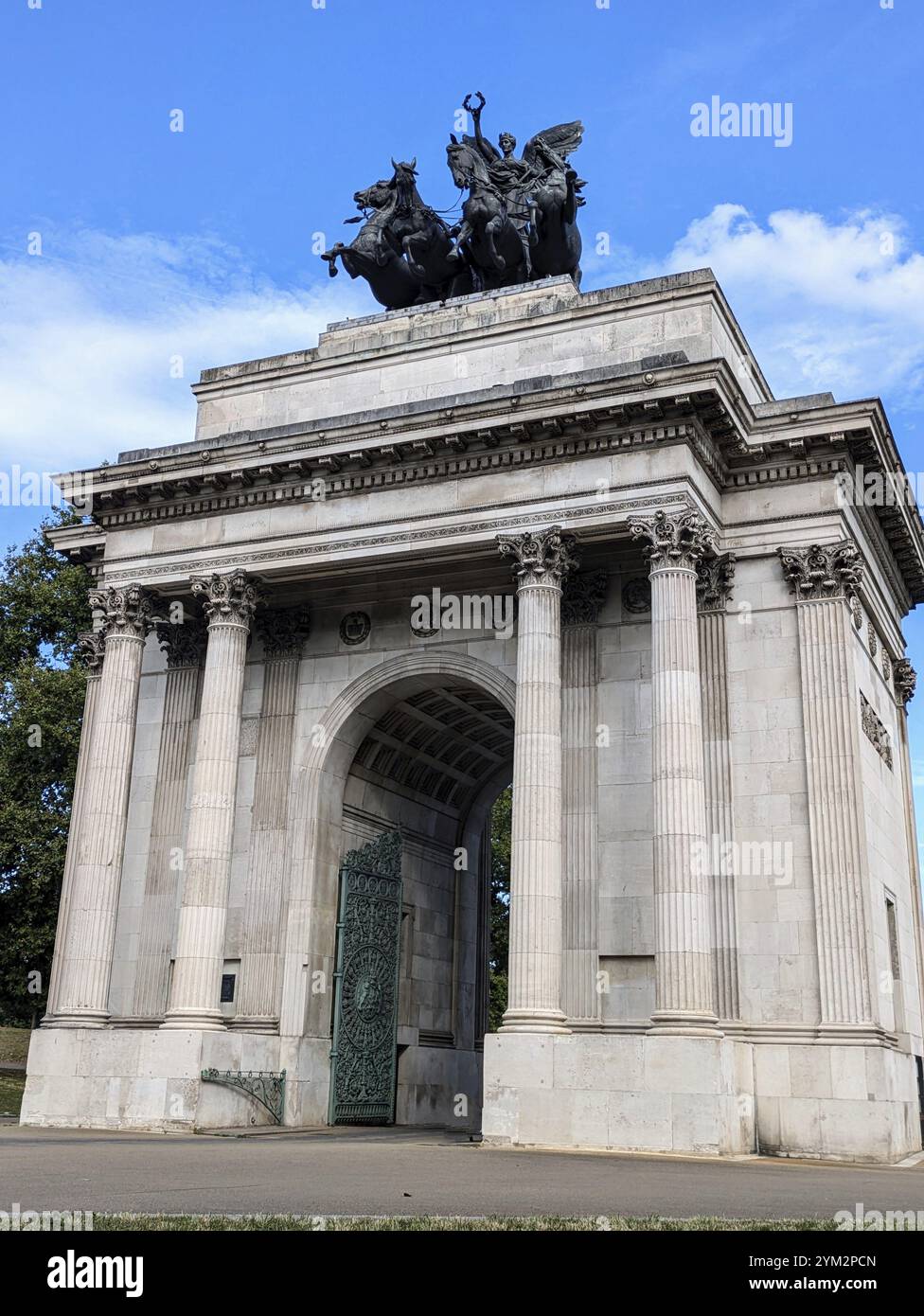 Neoclassical arch with sculptures and columns under a bright blue sky ...