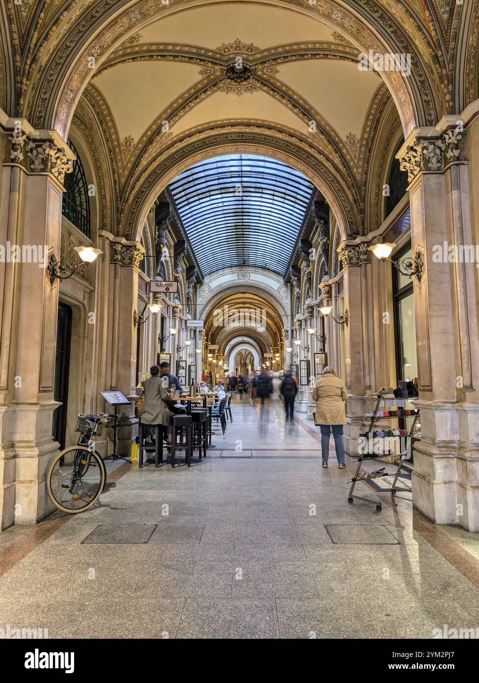 Ornate arcade interior with vaulted ceilings, showcasing people in a ...