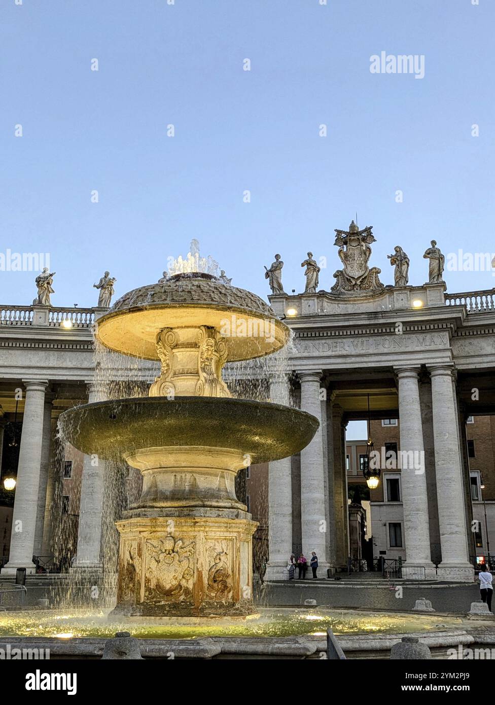 Illuminated fountain in a historical plaza, flanked by statues, with a ...
