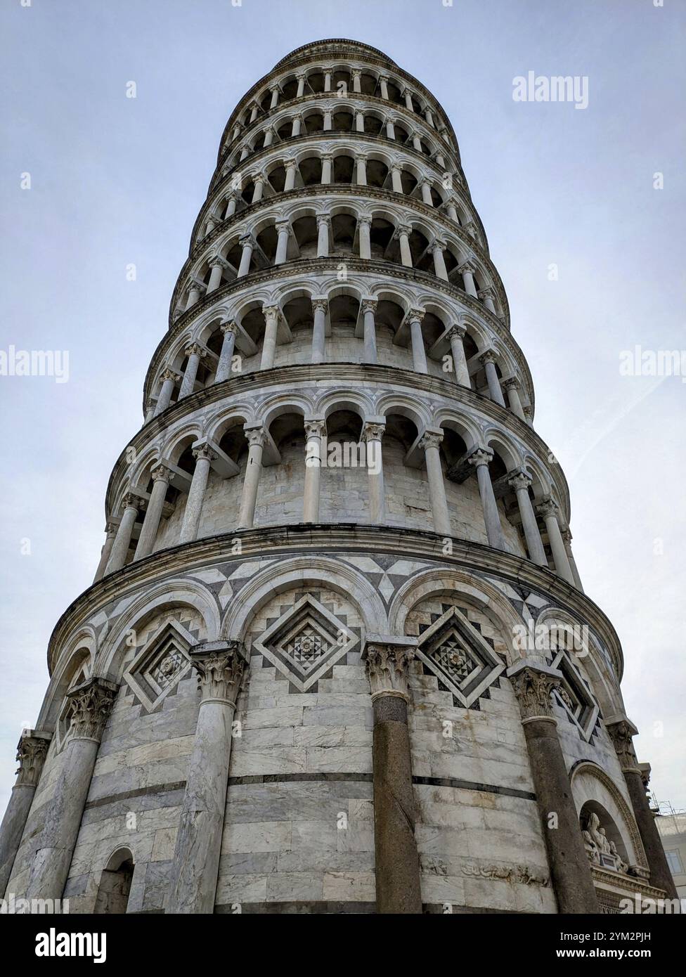 Close-up of the Leaning Tower of Pisa under an overcast sky, showcasing ...