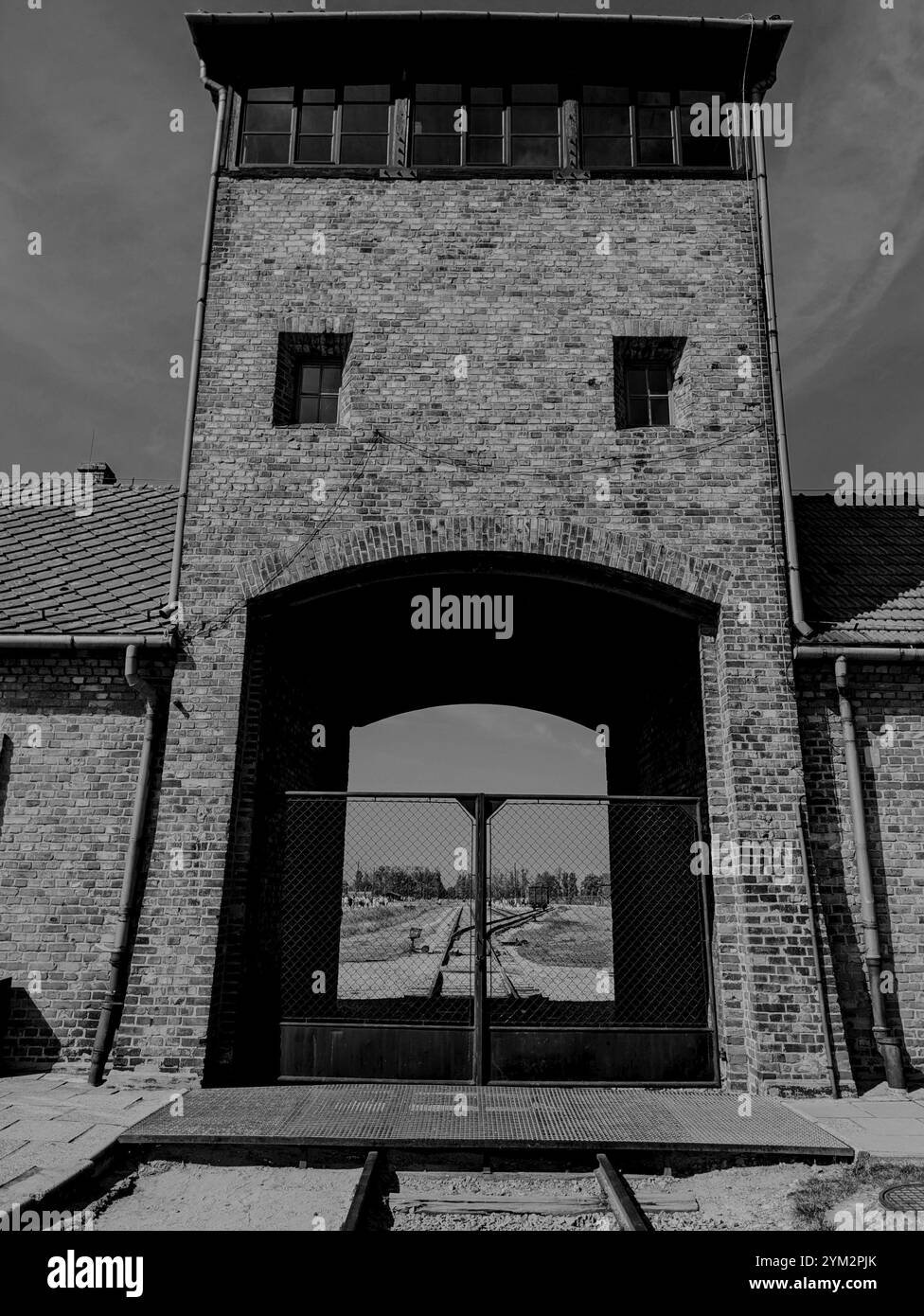 A historic brick building with a watchtower and gate, featuring rail ...