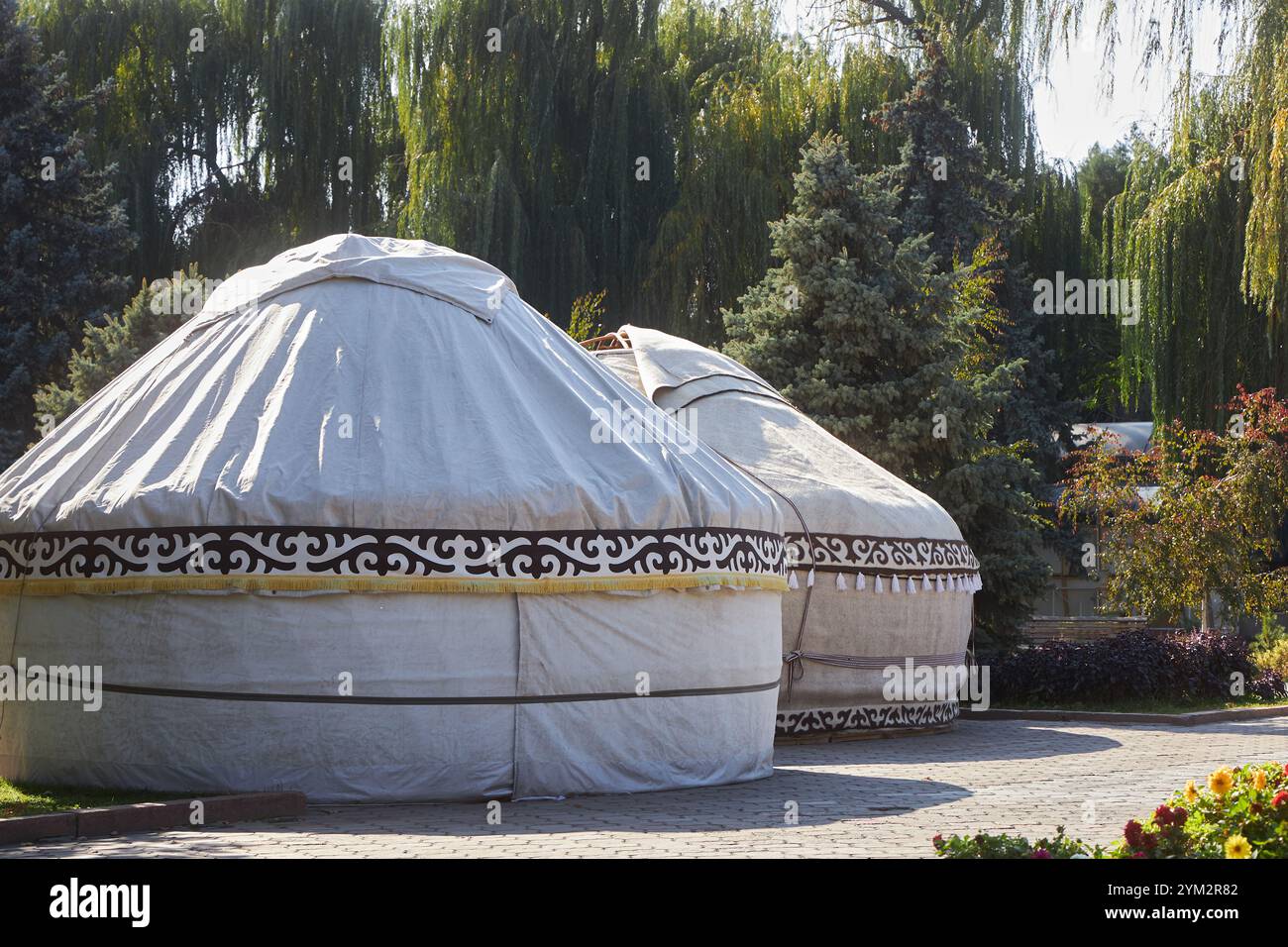 Two yurts surrounded by lush trees foliage in Bishkek city park ...
