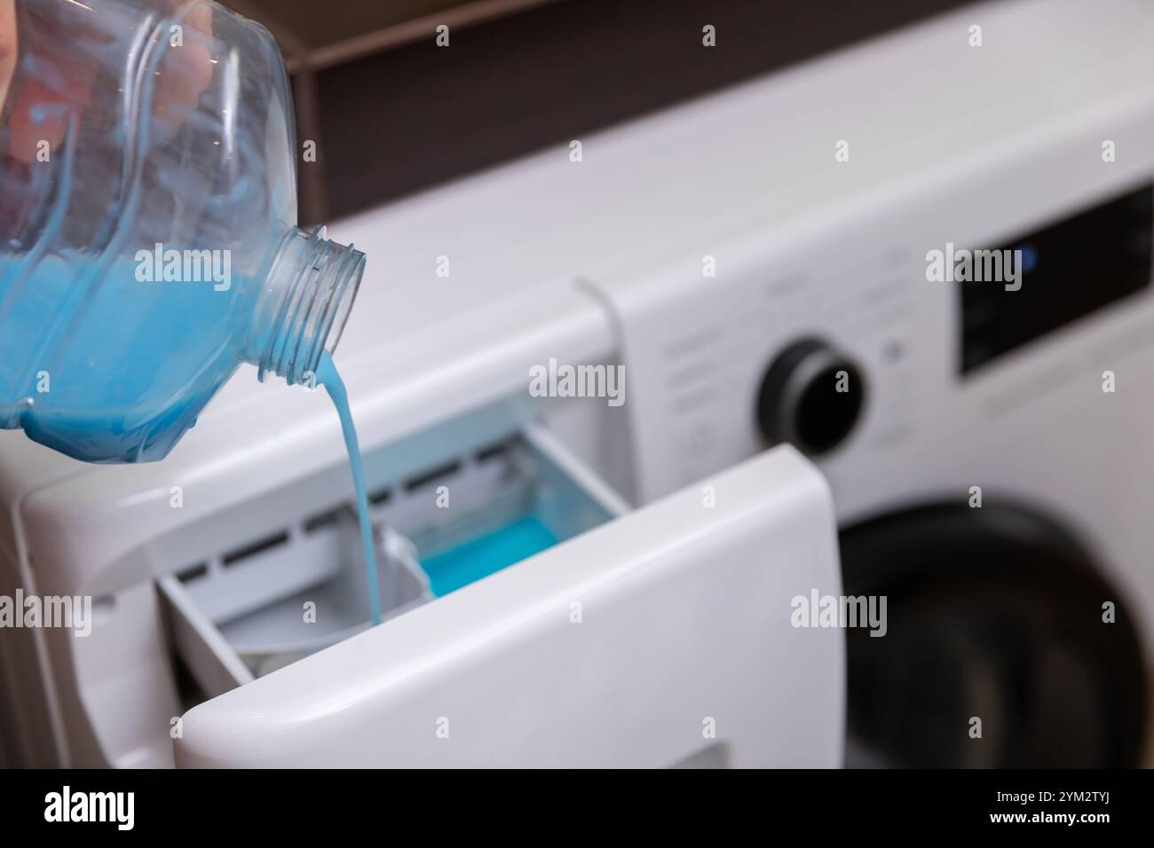 A closeup view shows laundry detergent being carefully poured into a ...