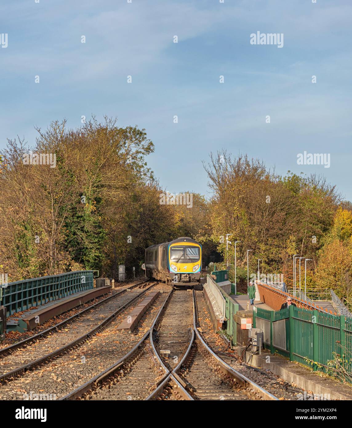 A train crosses over a railway bridge. A footbridge is to one side and ...