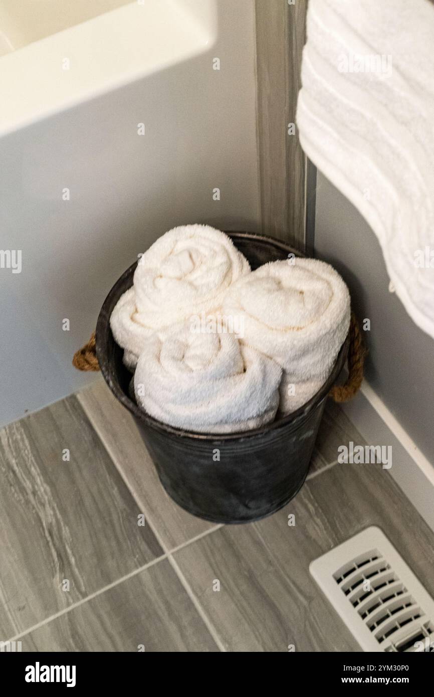 A bucket full of white towels is sitting on a tile floor. The towels ...