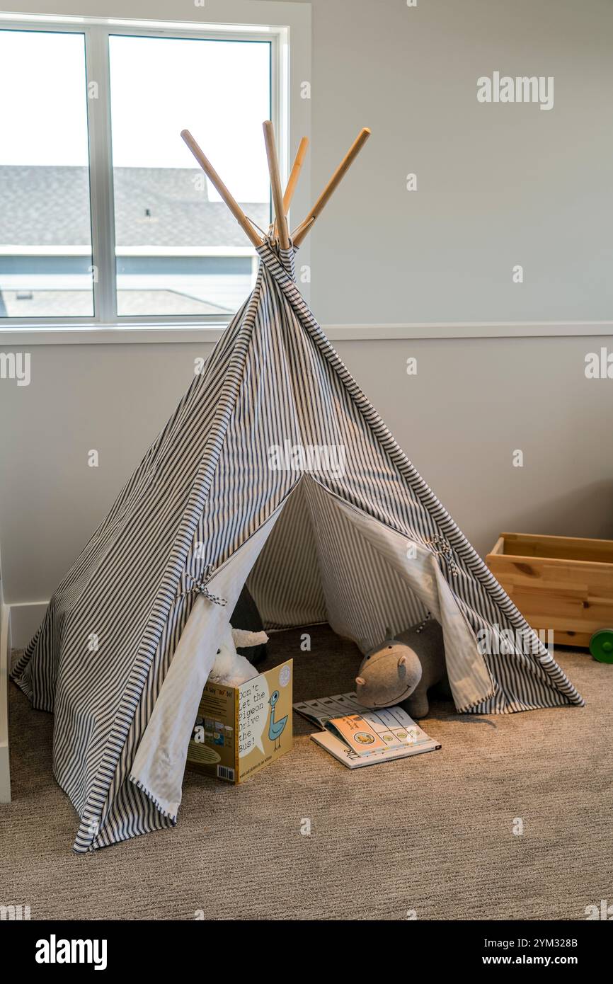 A teepee tent is set up in a room with a window. A stuffed animal is ...