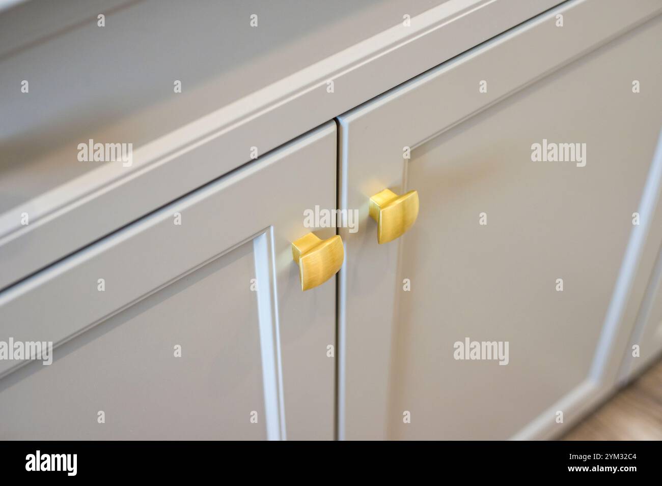 The cabinet has two gold knobs on the doors. The knobs are shiny and ...