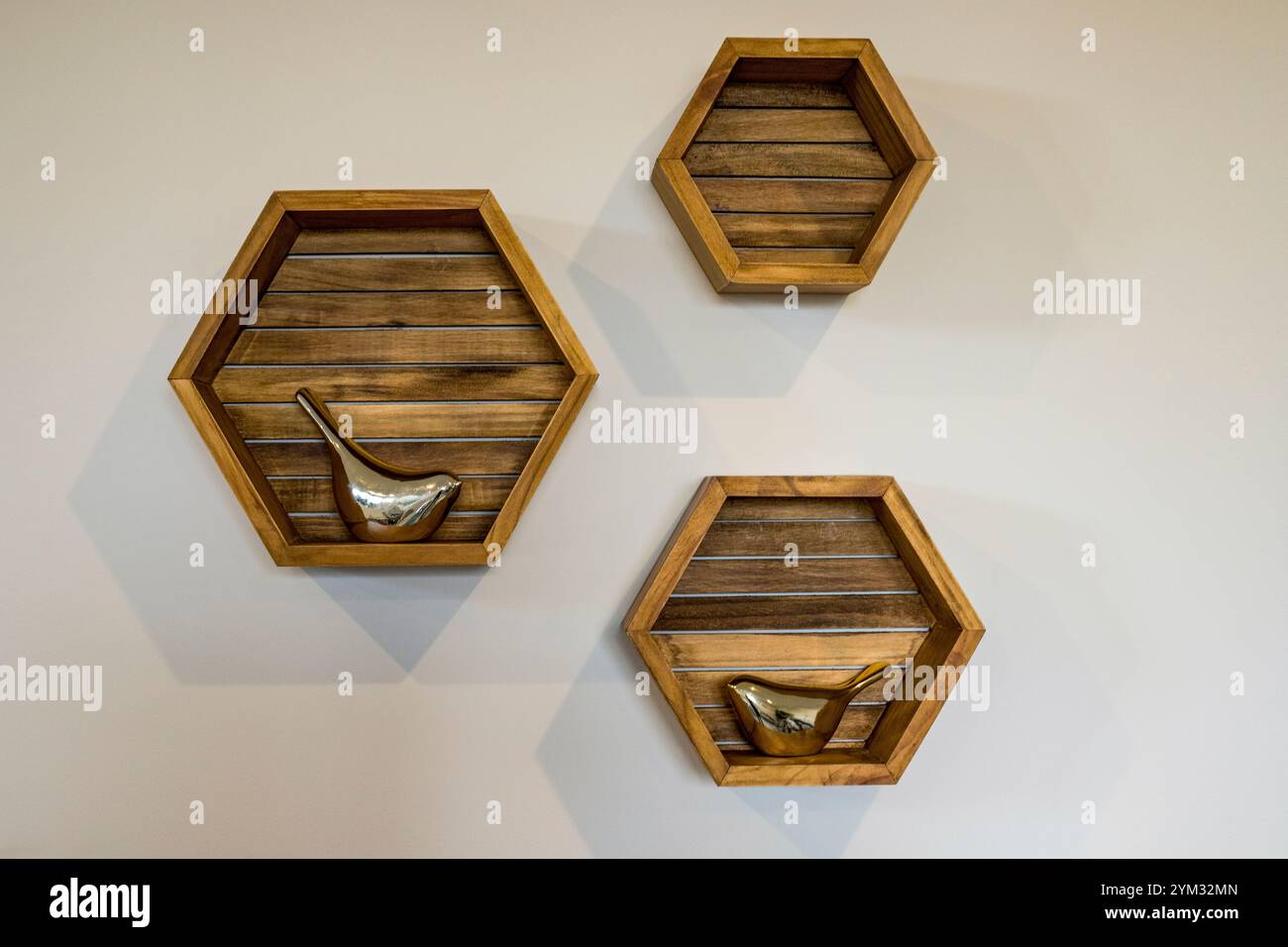 Three wooden hexagonal shelves with birds on them. The birds are gold ...