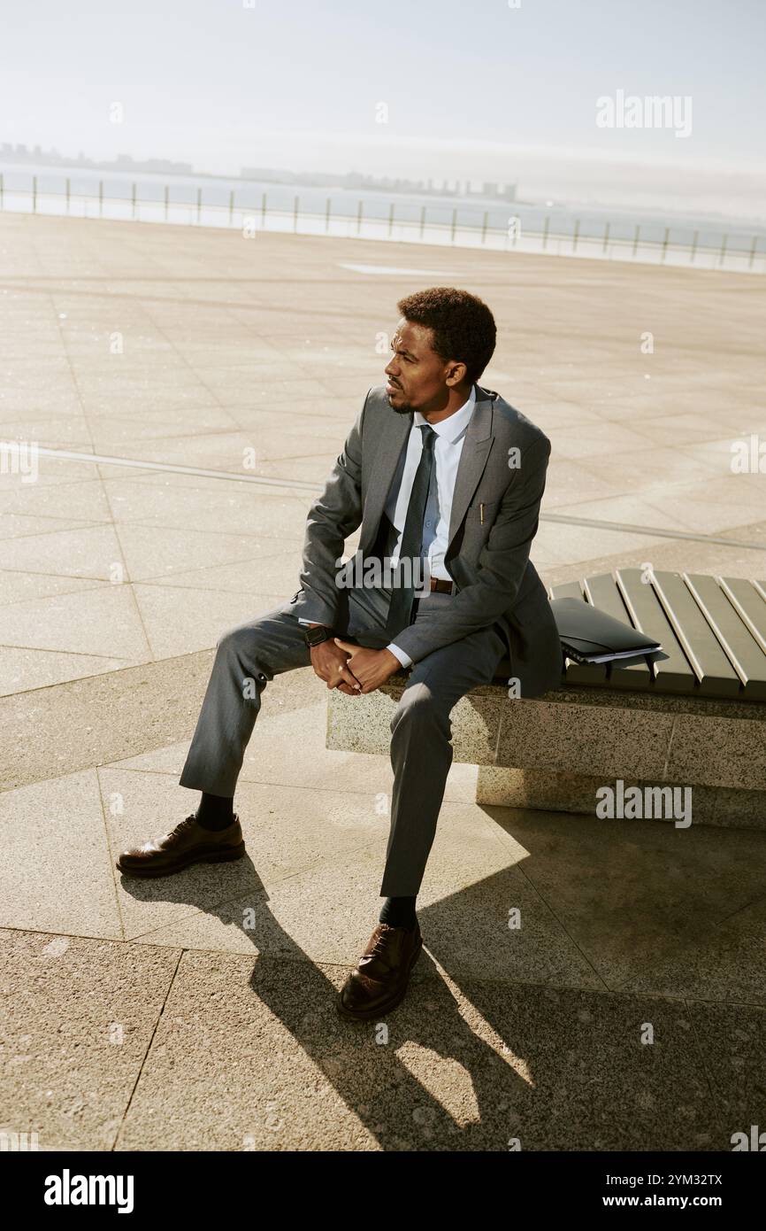 Businessperson in gray suit sitting on bench with ocean background ...