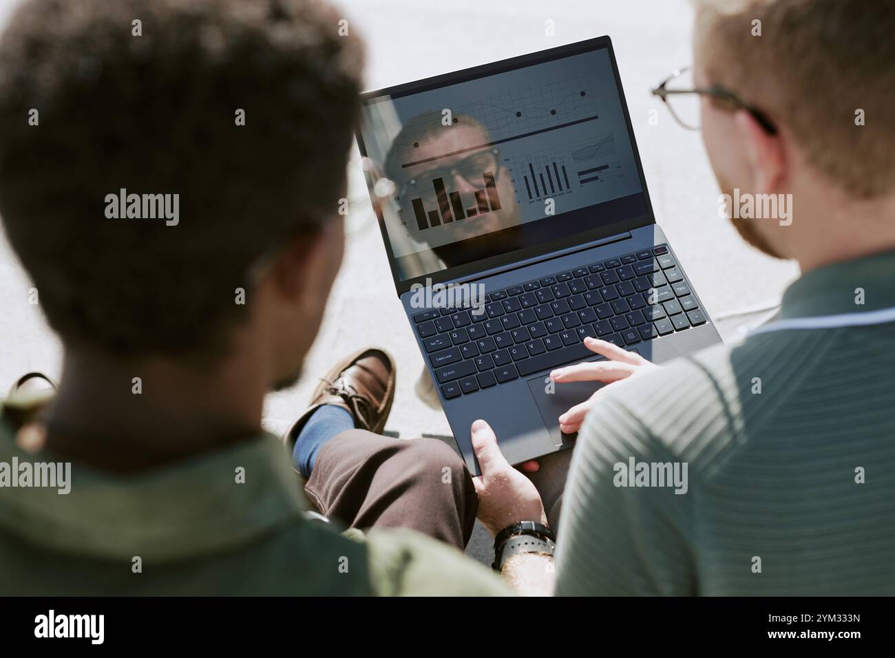 Two men reviewing business reports on laptop screen while sitting ...