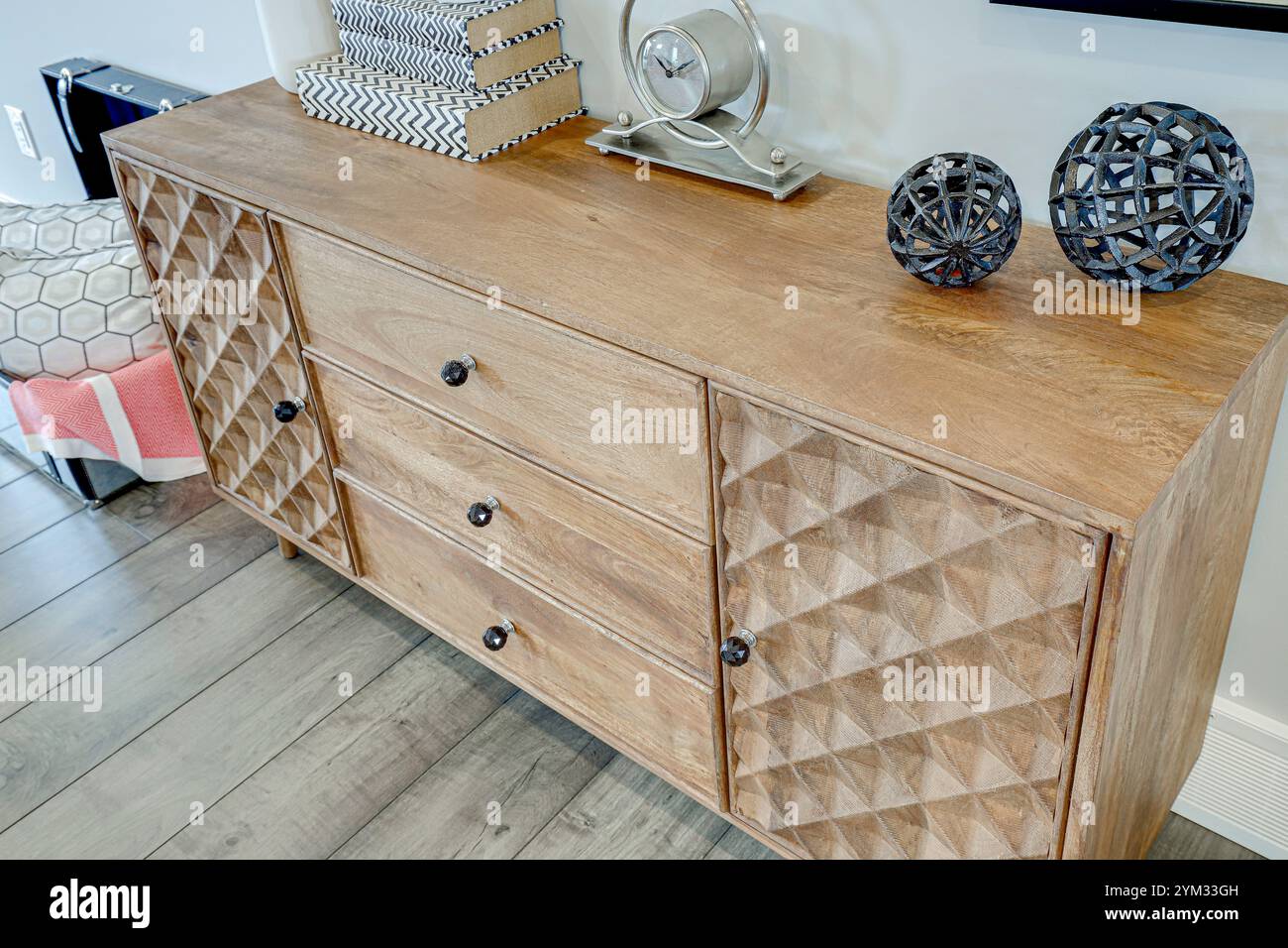 A wooden dresser with three drawers and a clock on top. The clock is ...