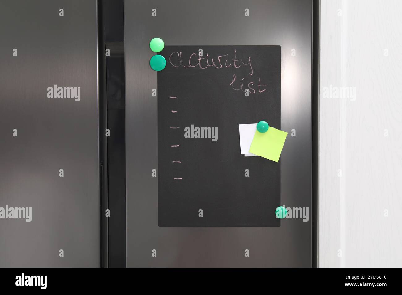 Magnetic board with activity list and notes on refrigerator in kitchen ...