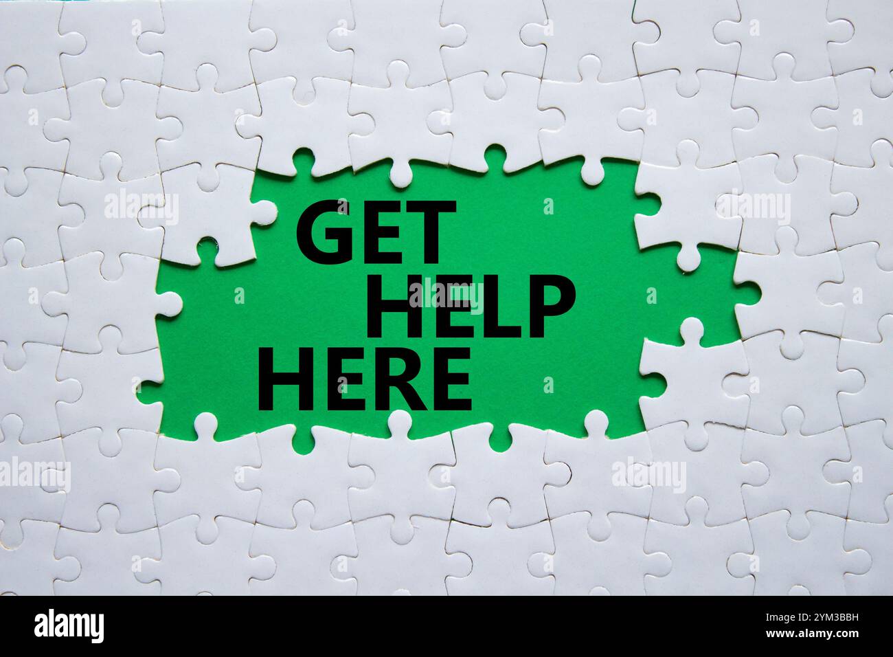 Get help here symbol. White puzzle with words Get help here. Beautiful green background ...