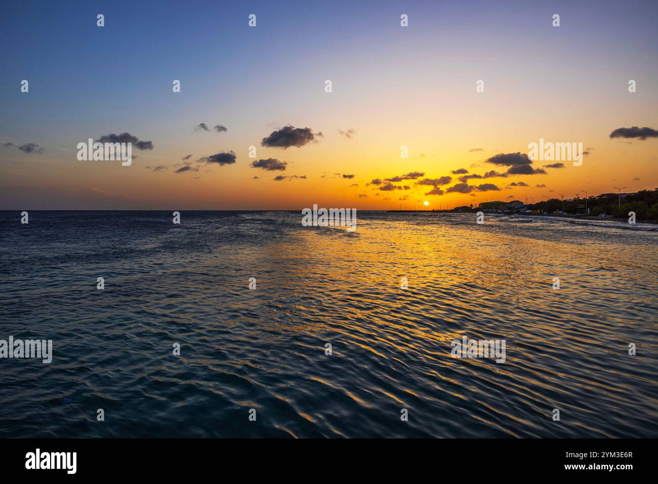 Golden sunset over Caribbean Sea with calm waves and scattered clouds ...