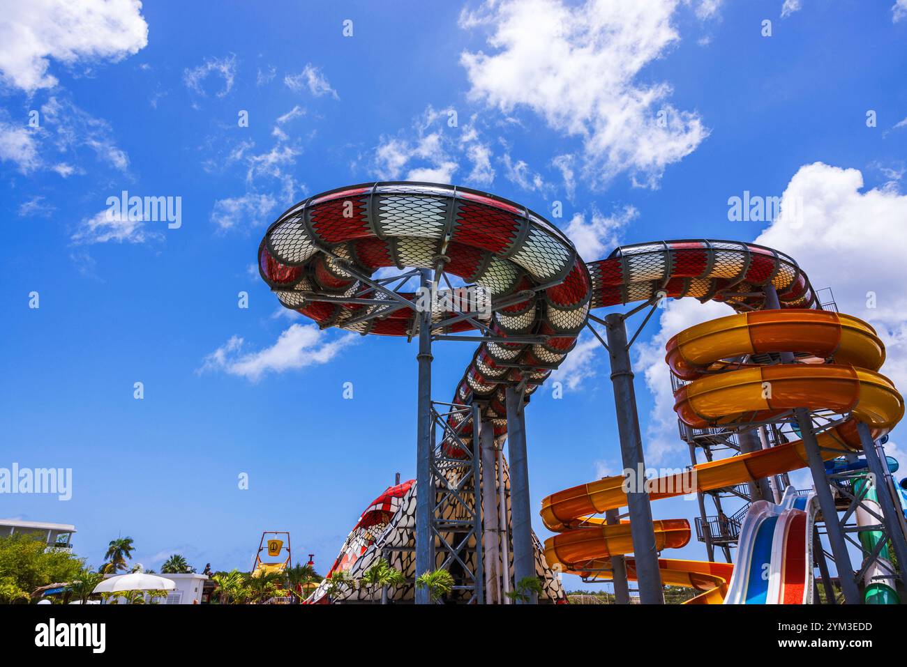 Brightly colored water slides twisting under clear blue sky at tropical ...
