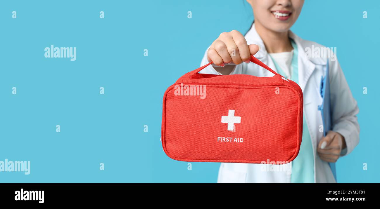 Female doctor holding first aid kit on light blue background with space ...