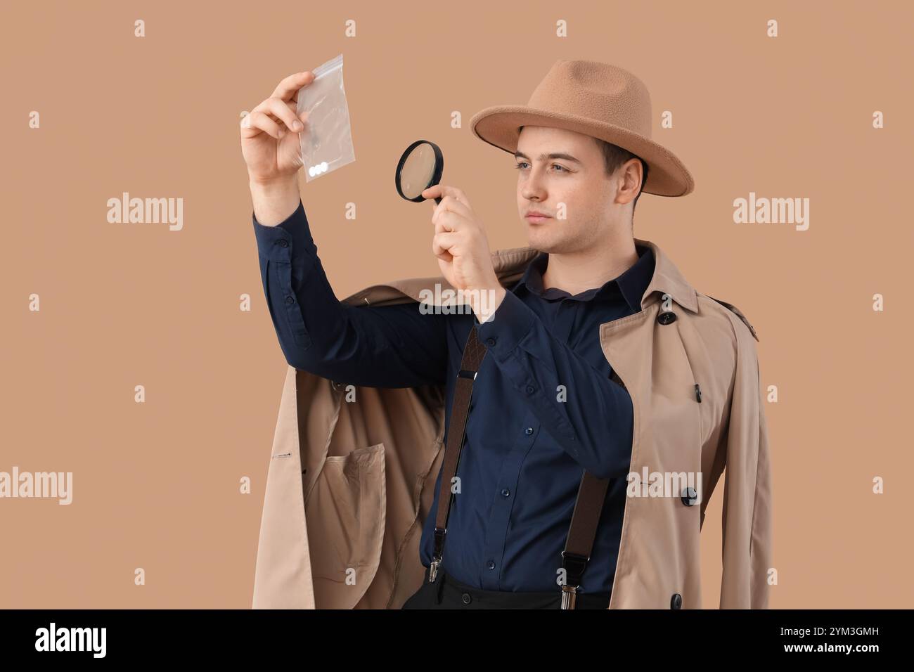 Male detective with magnifier examining evidence on beige background ...