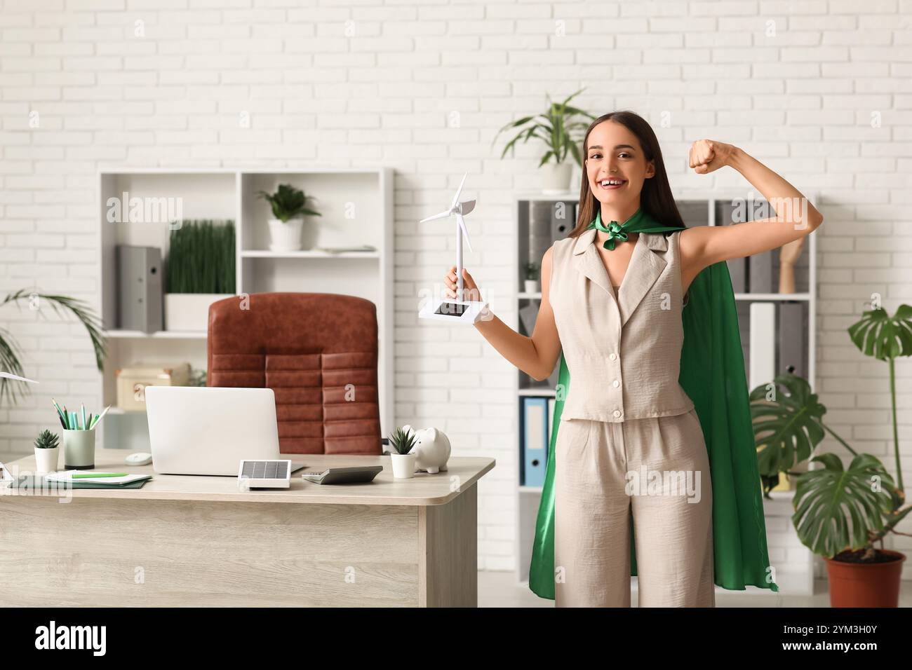 Female engineer in superhero cape with wind turbine model at office ...