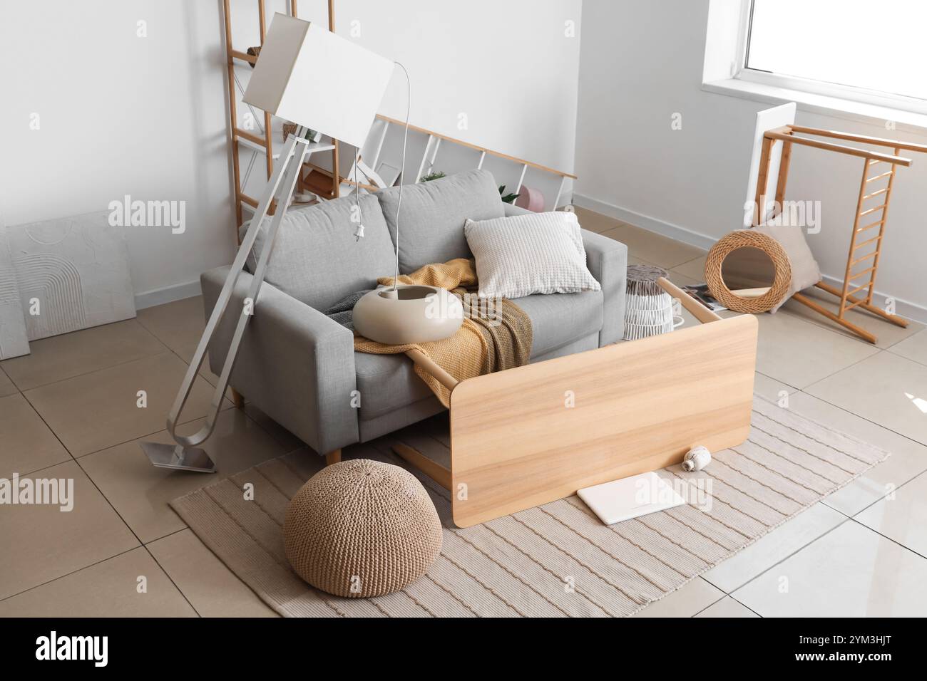 Interior of messy living room with grey sofa and overturned furniture ...