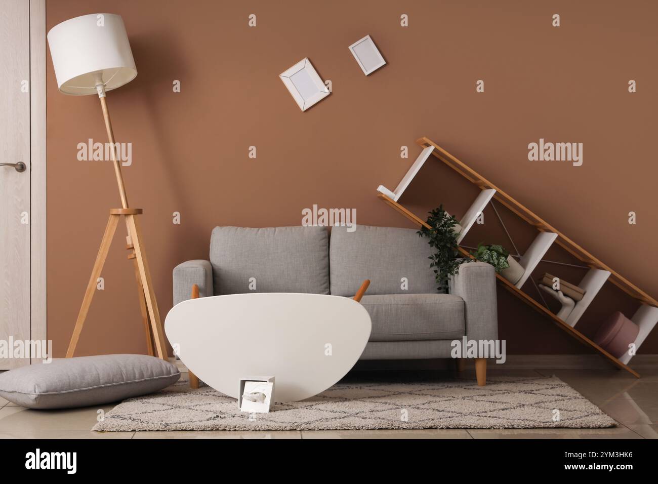 Interior of messy living room with grey sofa and overturned furniture ...