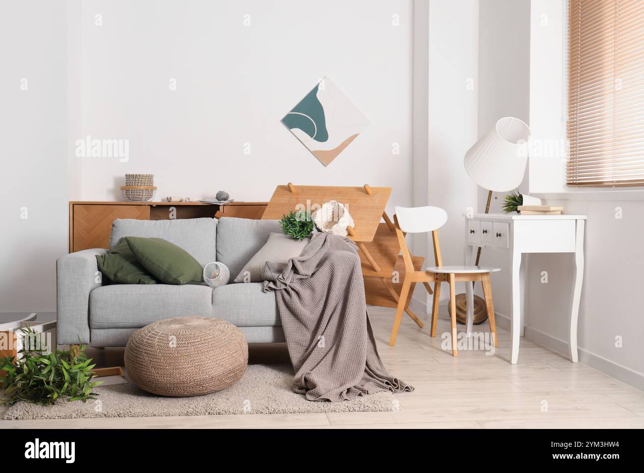 Interior of messy room with grey sofa and overturned furniture after ...