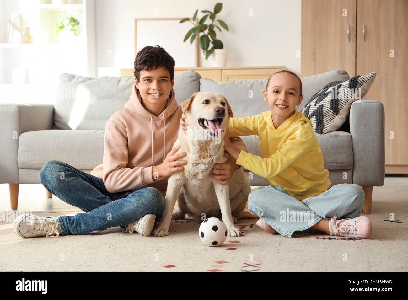 Happy sister and brother with cute Labrador dog sitting on floor at ...