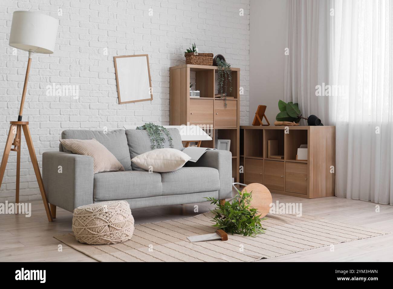 Interior of messy room with grey sofa and overturned furniture after ...