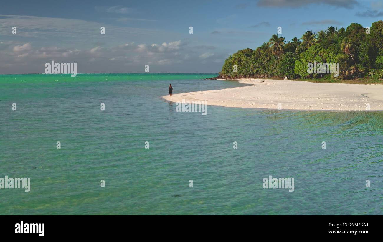 Lone woman is walking on a pristine white sand beach on the tropical ...