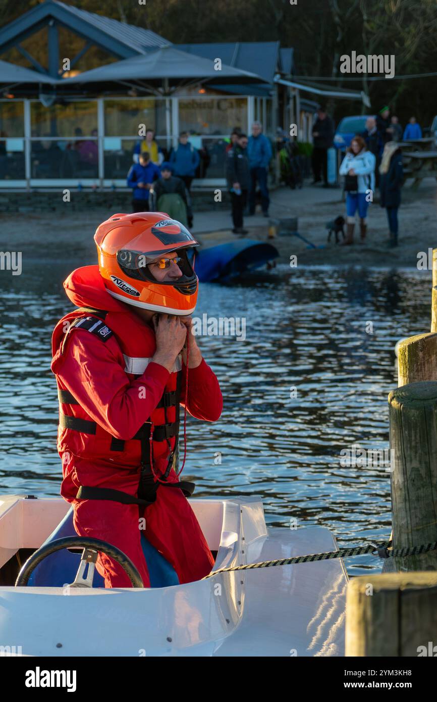 Powerboat driver wearing bright orange overalls standing in his boat in ...