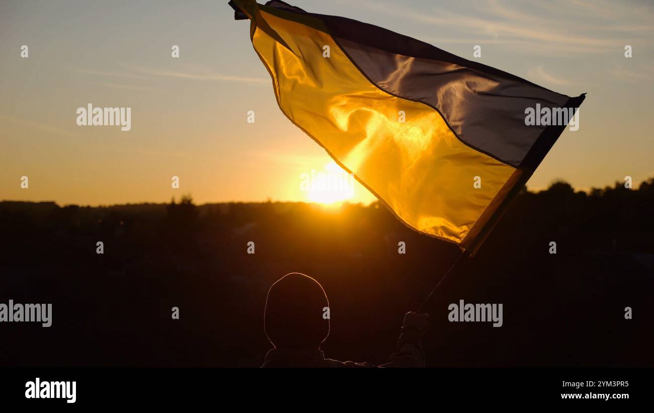 Young man in military uniform waving flag of Ukraine against beautiful ...