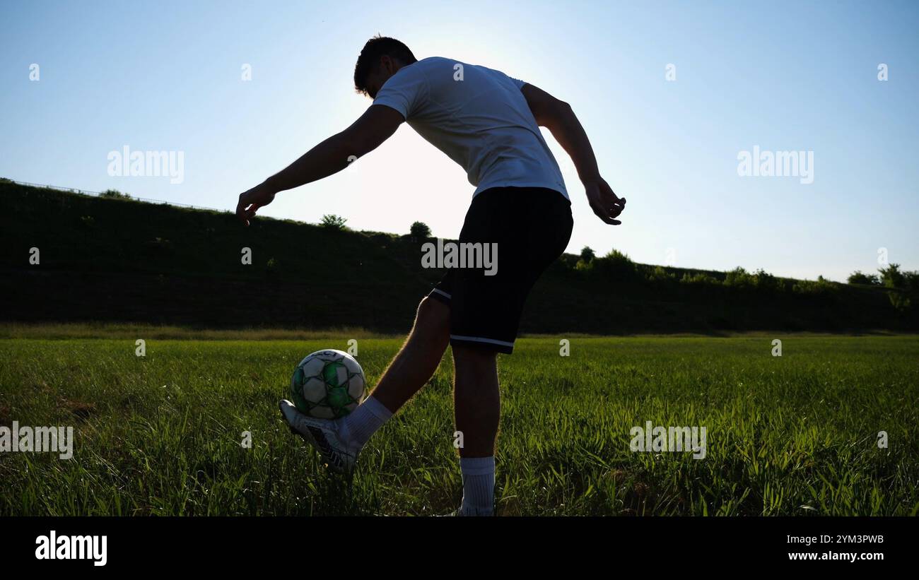 Sportsman juggling soccer ball on stadium at sunny day. Young man ...