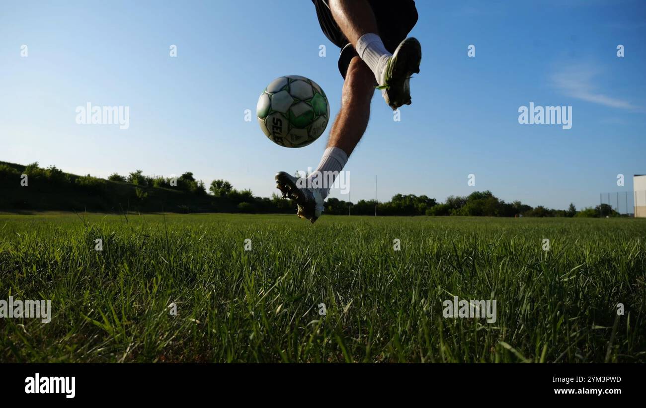 Sportsman juggling soccer ball on stadium at sunny day. Young man ...