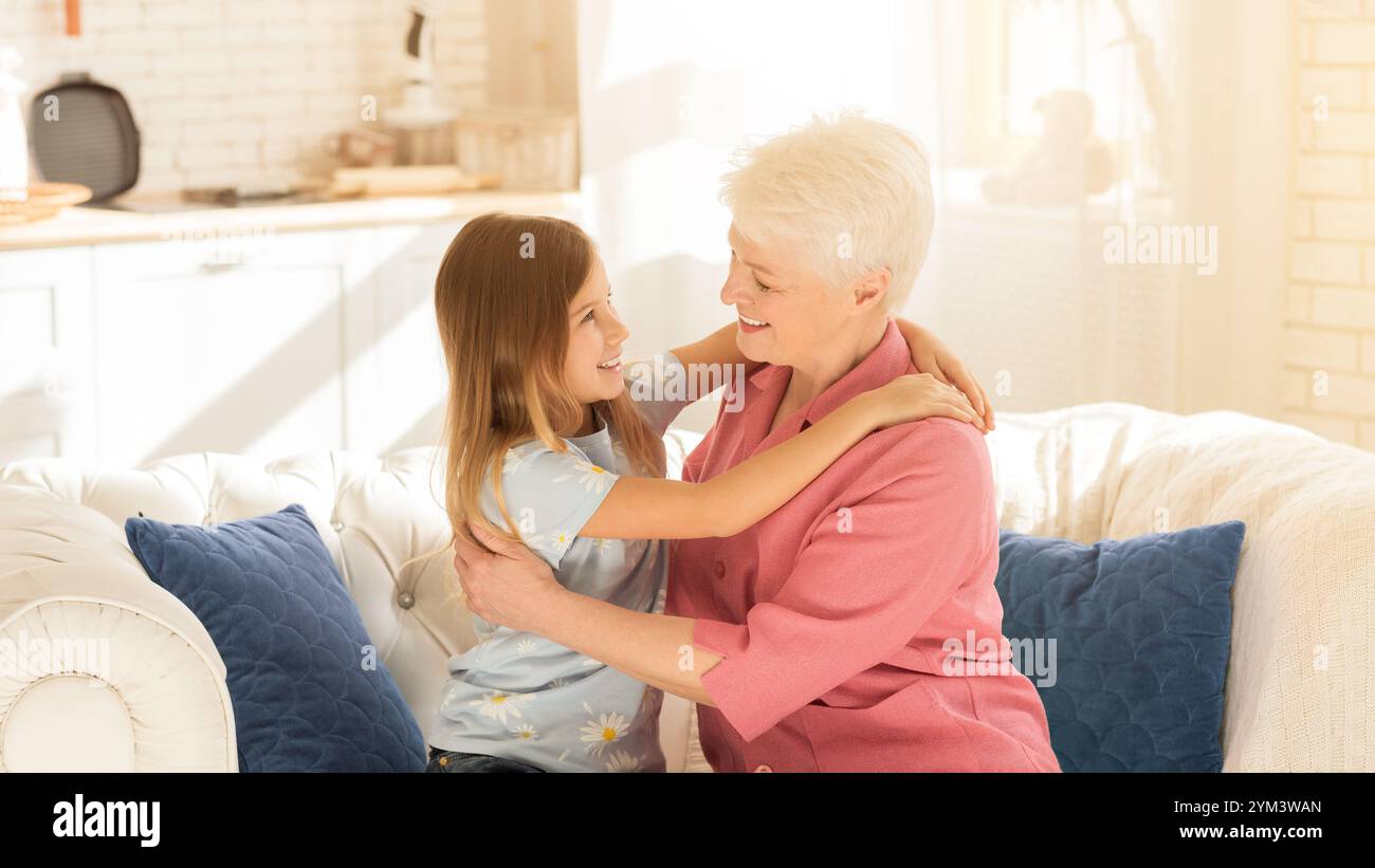 Little child and her grandmother hugging each other on sofa Stock Photo ...