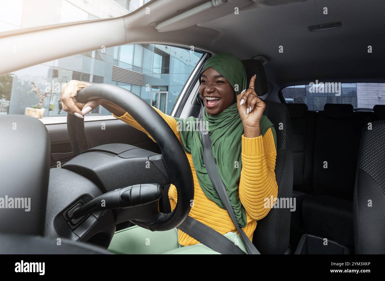 Happy muslim black female driver singing and dancing while driving car ...