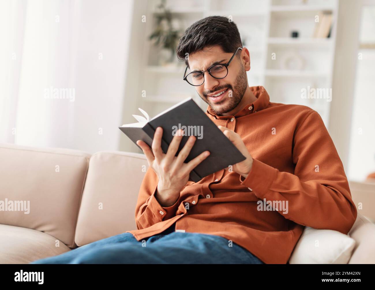 Young Arab man in glasses reading book Stock Photo - Alamy