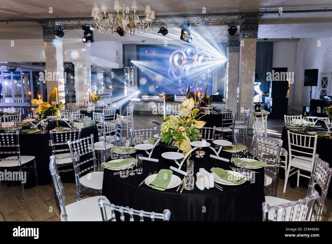 Elegant banquet hall with floral centerpieces, table settings, dramatic stage lighting for ...