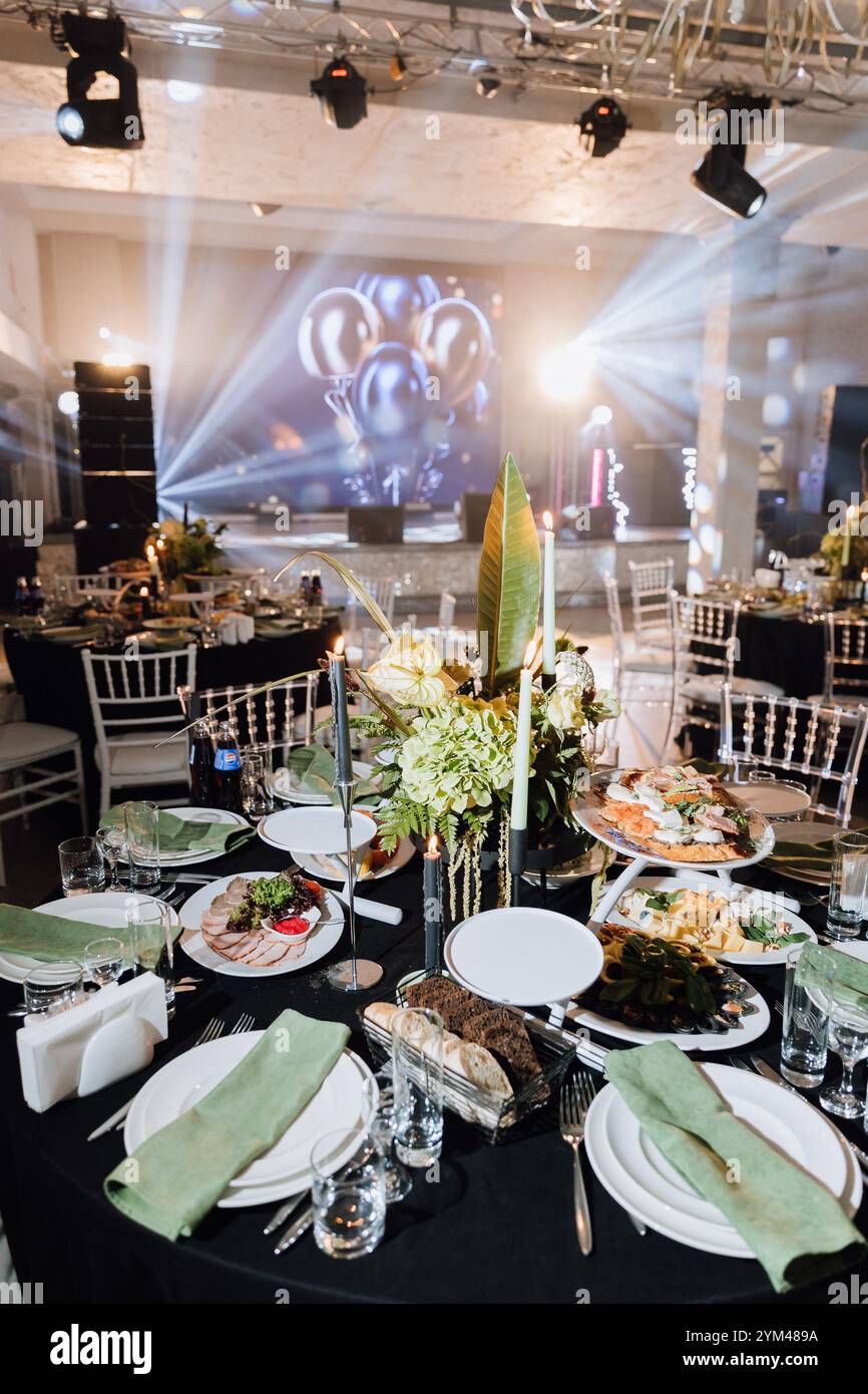 Elegant banquet hall with floral centerpieces, table settings, dramatic stage lighting for ...