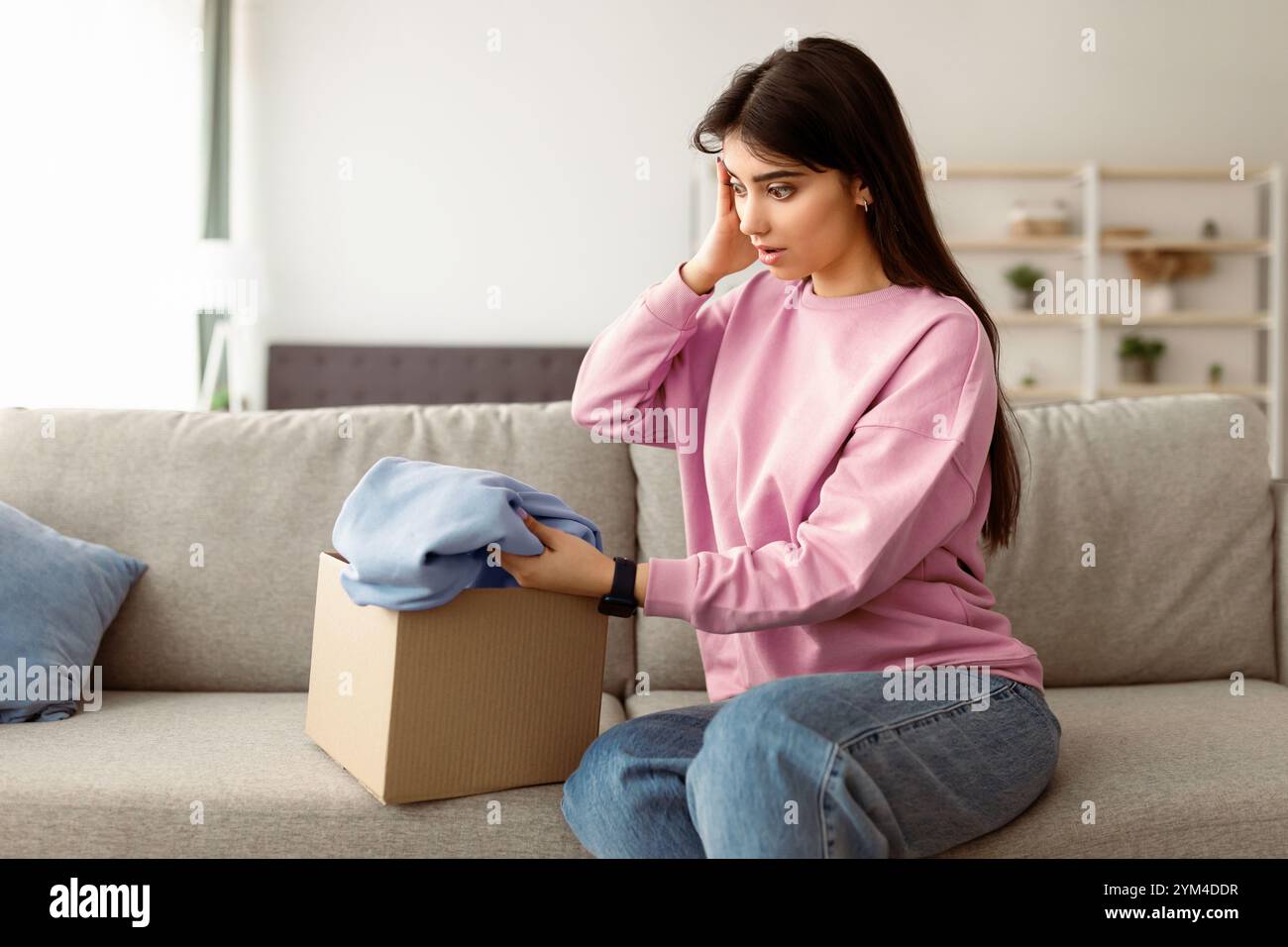 Shocked young woman unpacking wrong parcel, delivery mistake Stock ...