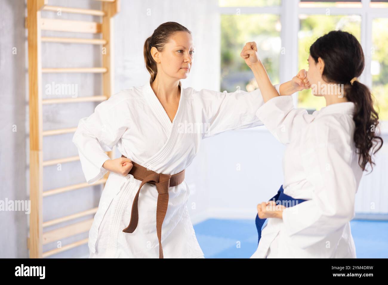 Two woman in kimono sparring together in gym during karate training ...