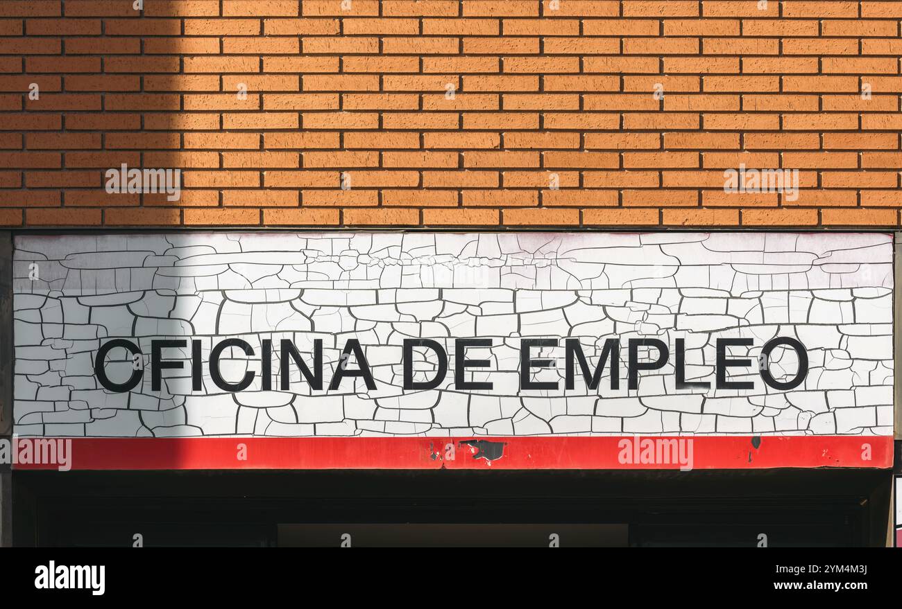 Employment office sign in Spanish on a brick wall indicating job ...
