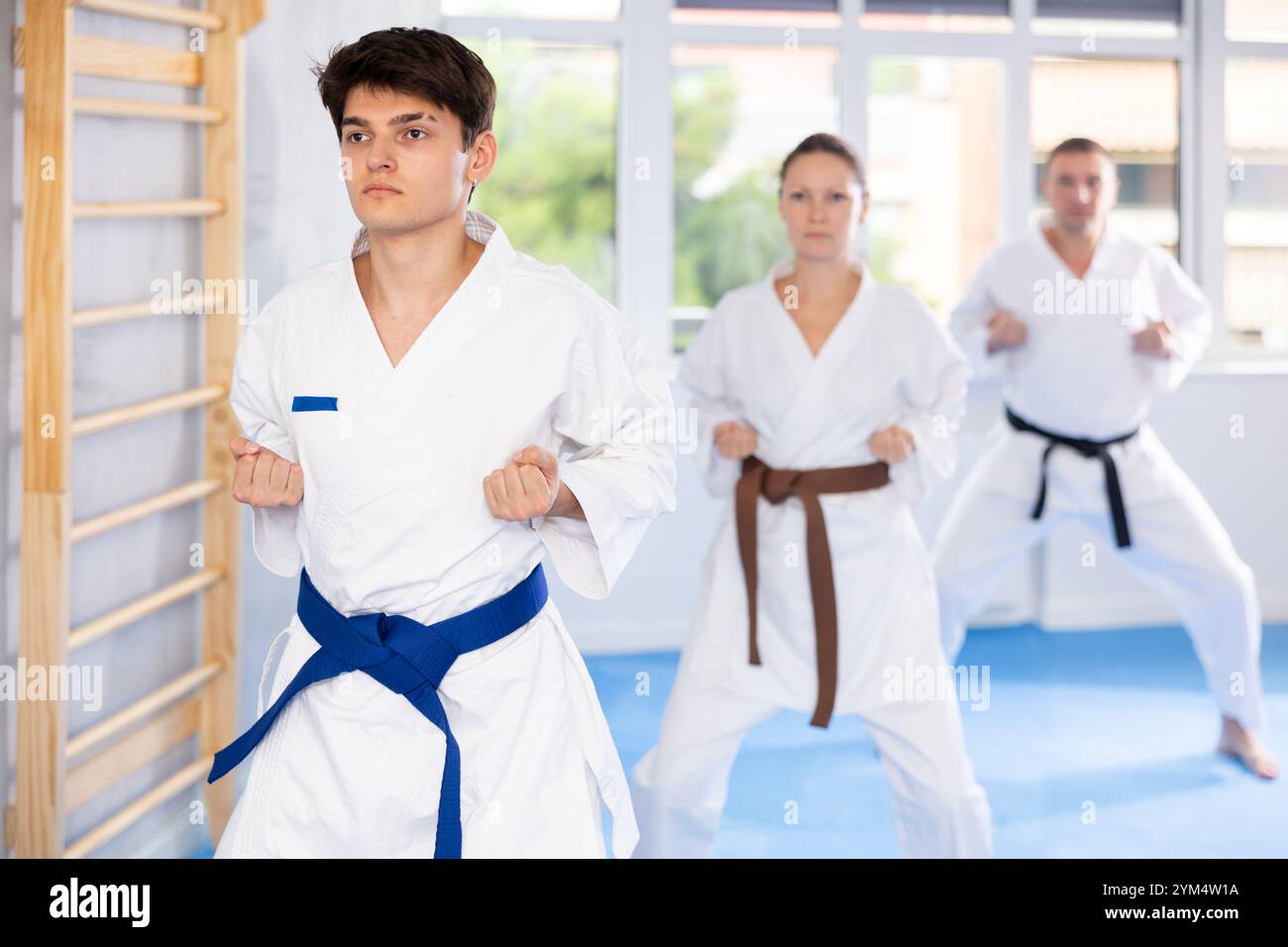 Woman and man in kimono standing in fight stance during group karate ...