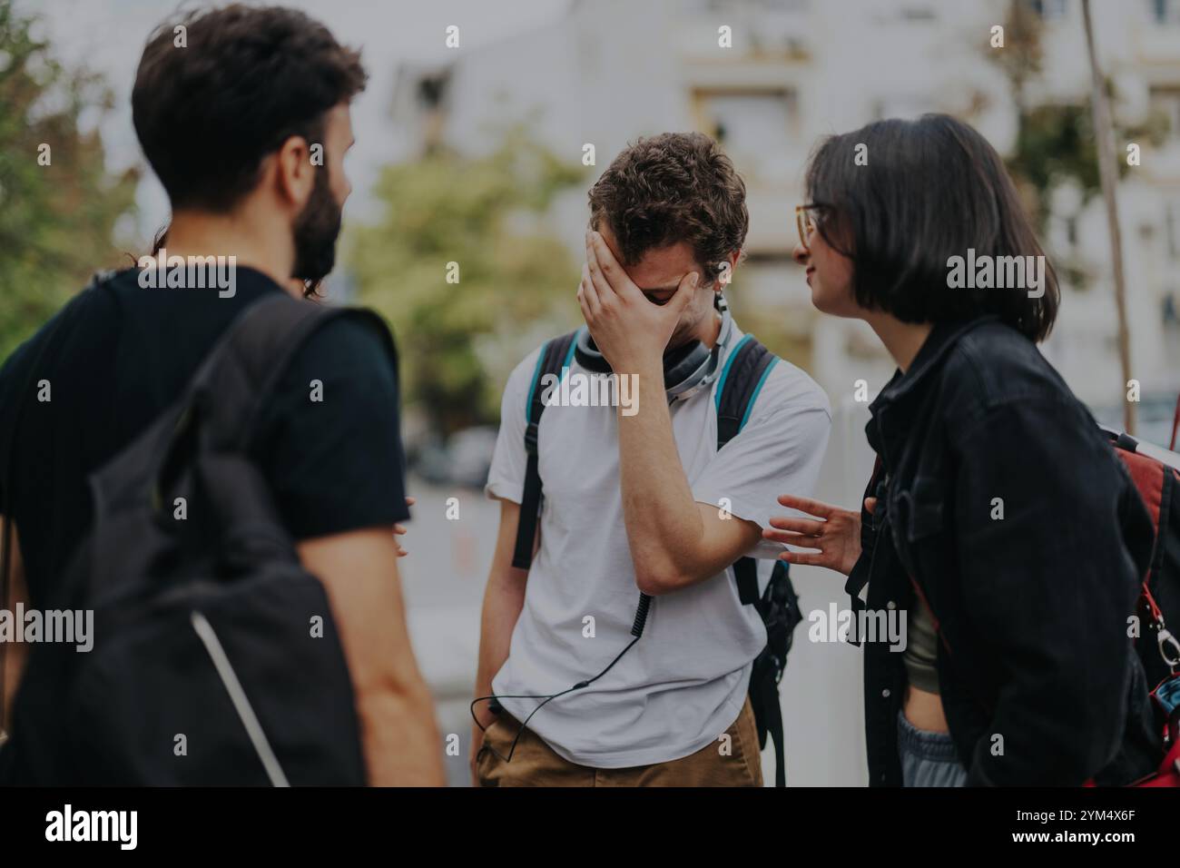 Three friends having an intense conversation outdoors with emotional ...
